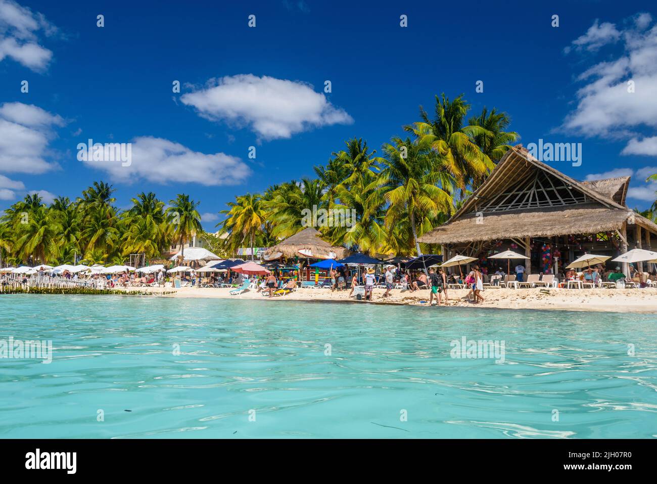 People sunbathing on the white sand beach with umbrellas, bungalow bar ...