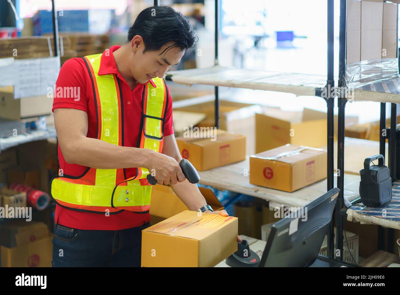 Asian warehouse man worker with computer and barcode scanner in ...
