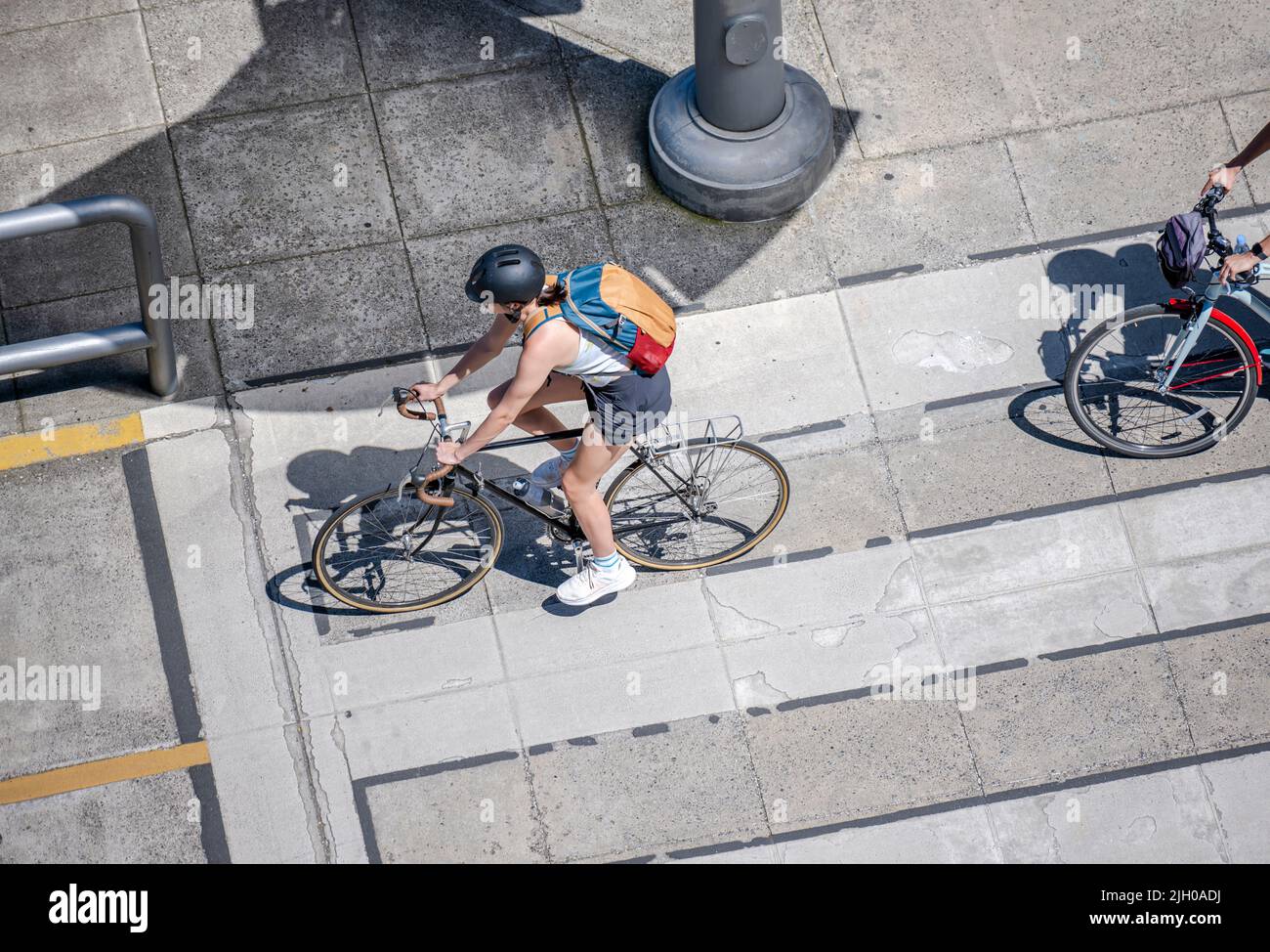 Group of amateur cyclists ride bicycles along the city sidewalk ...