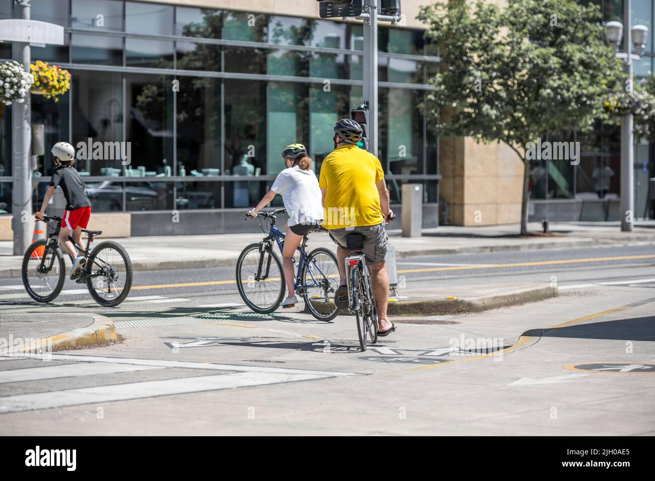 Family group of amateur cyclists ride bicycles along the city sidewalk ...