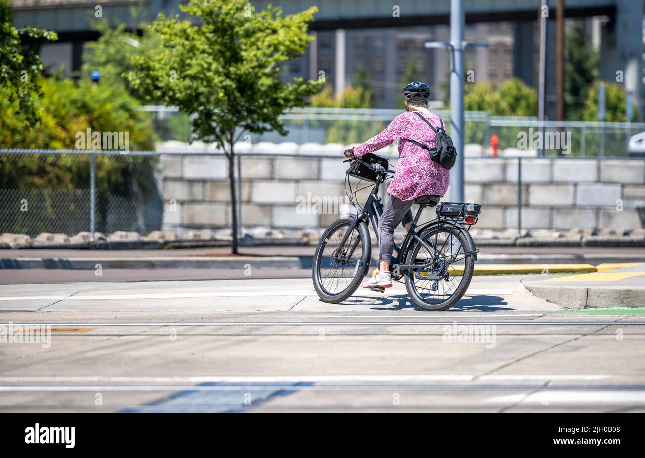 Slender woman on a bike rides a bicycle along the concrete city ...