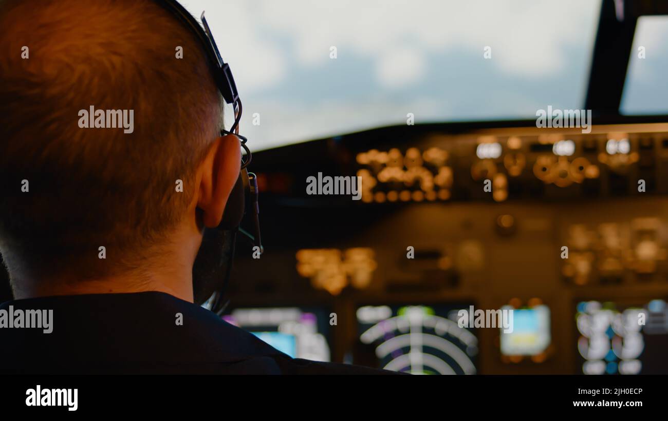 Male aviator using handle and windscreen in cockpit to fly airplane ...