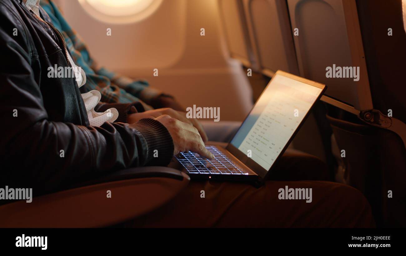 Tired employee travelling by airplane and working on laptop, using ...