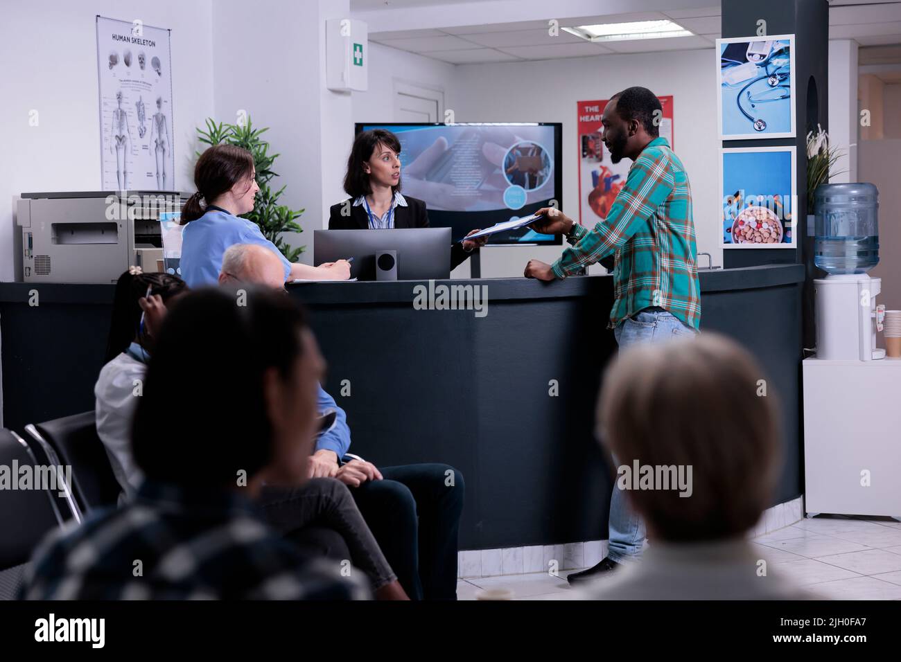 African american patient handing clipboard with completed form to ...