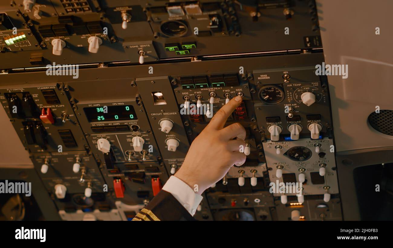 Male captain pushing dashboard buttons to start airplane engine, using ...