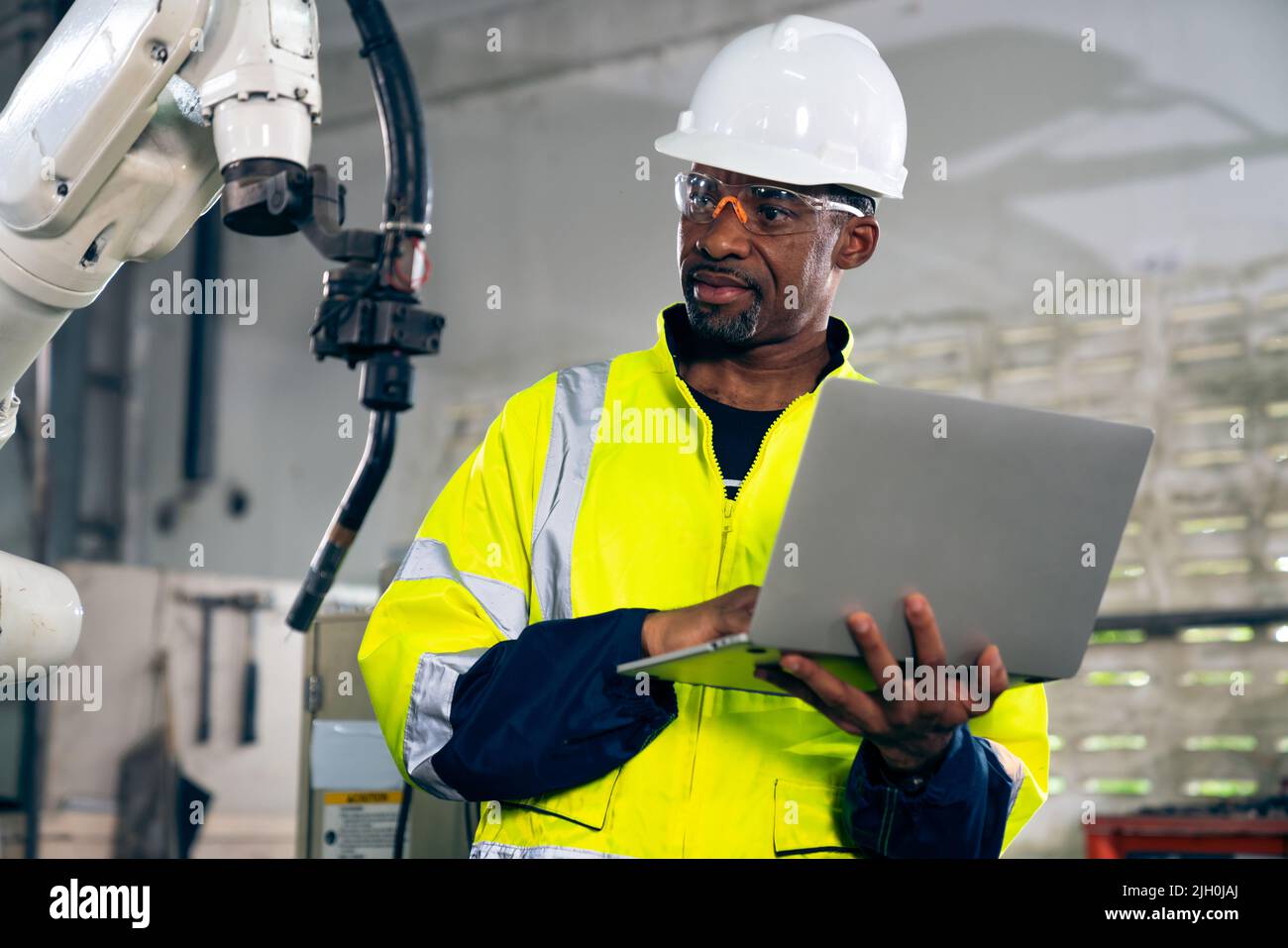 African American factory worker working with adept robotic arm in a ...