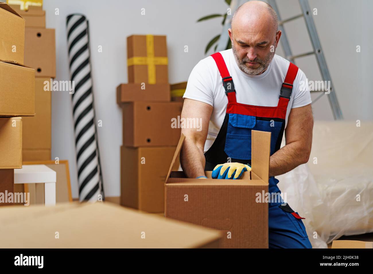 Man mover in uniform packing boxes for relocation Stock Photo - Alamy