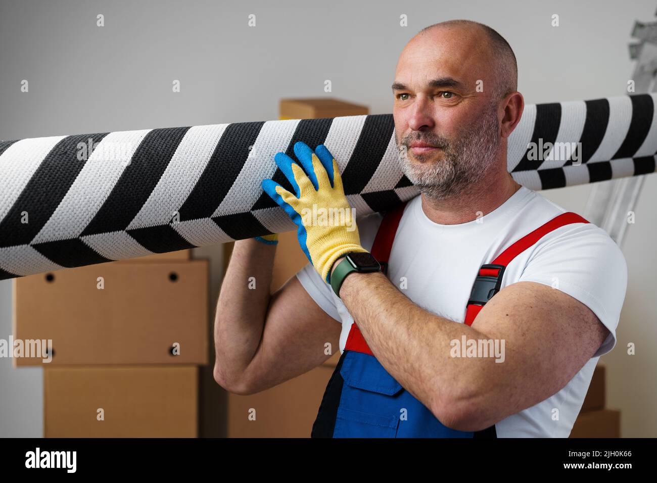 Man mover in uniform carrying big rolled carpet for relocation Stock ...