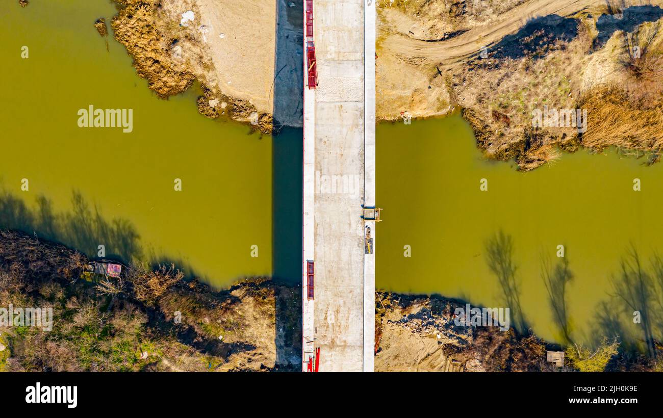 Above top view, overhead, on unfinished bridge, road over river under ...