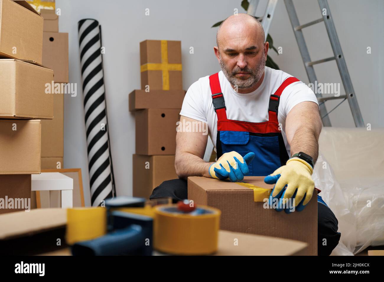 Man mover in uniform packing boxes for relocation Stock Photo - Alamy