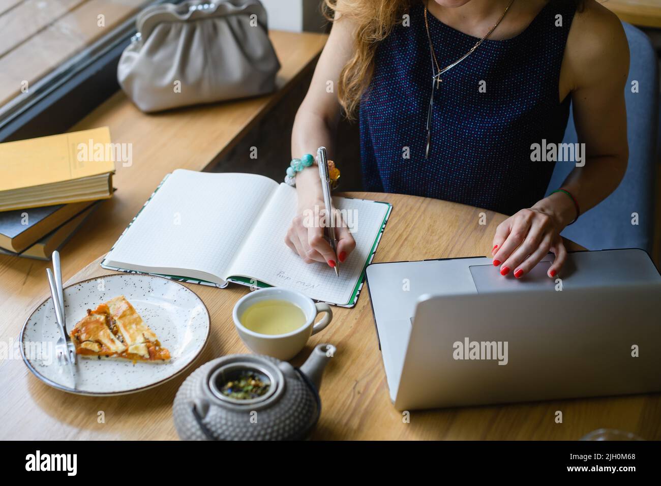A woman makes a note in her notebook while sitting in a cafe. Pie ...