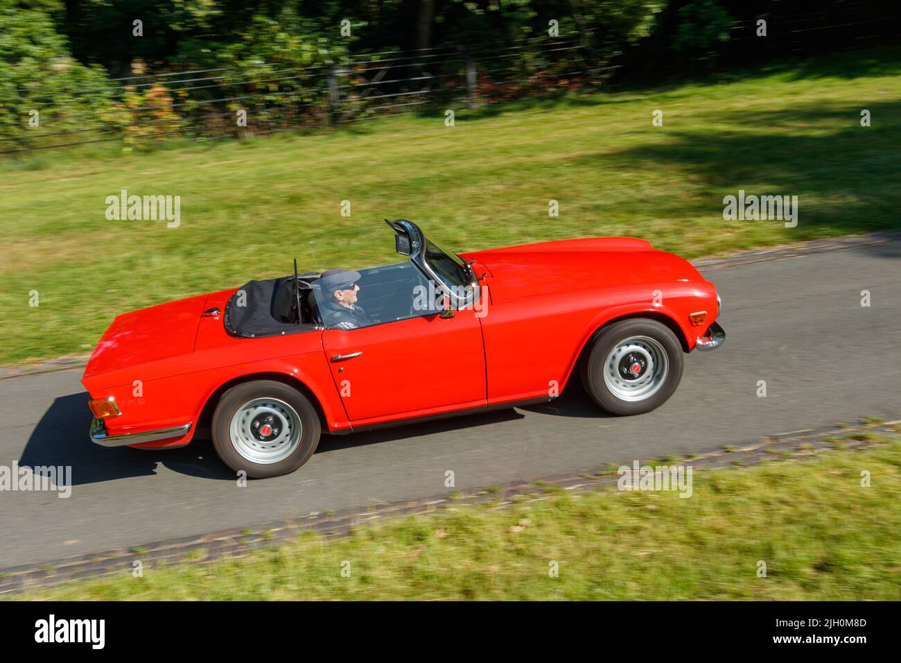 classic vintage red 1970s triumph TR6 sports car panning shot driving ...
