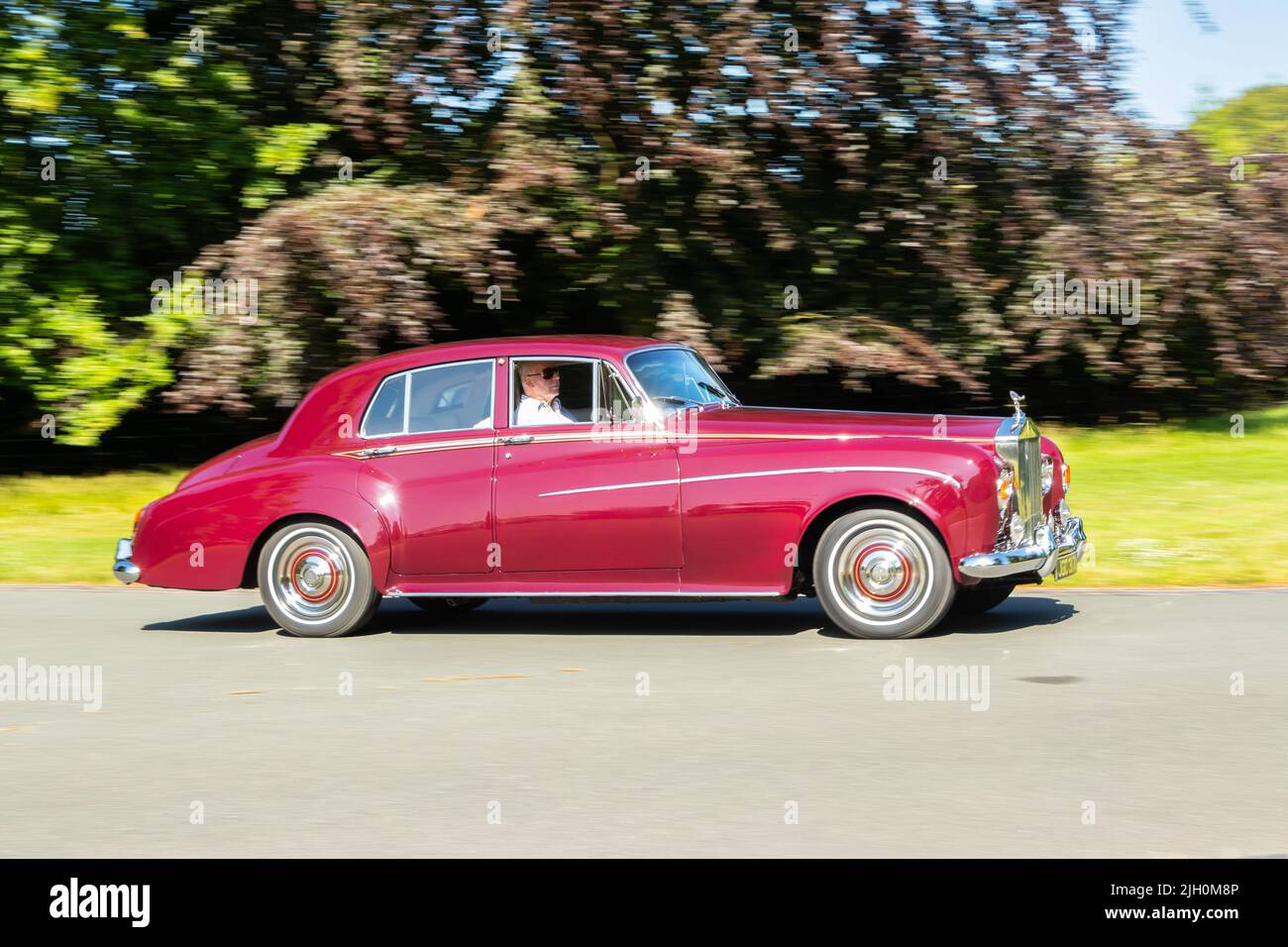 panning shot of classic red rolls royce driving along road Stock Photo ...