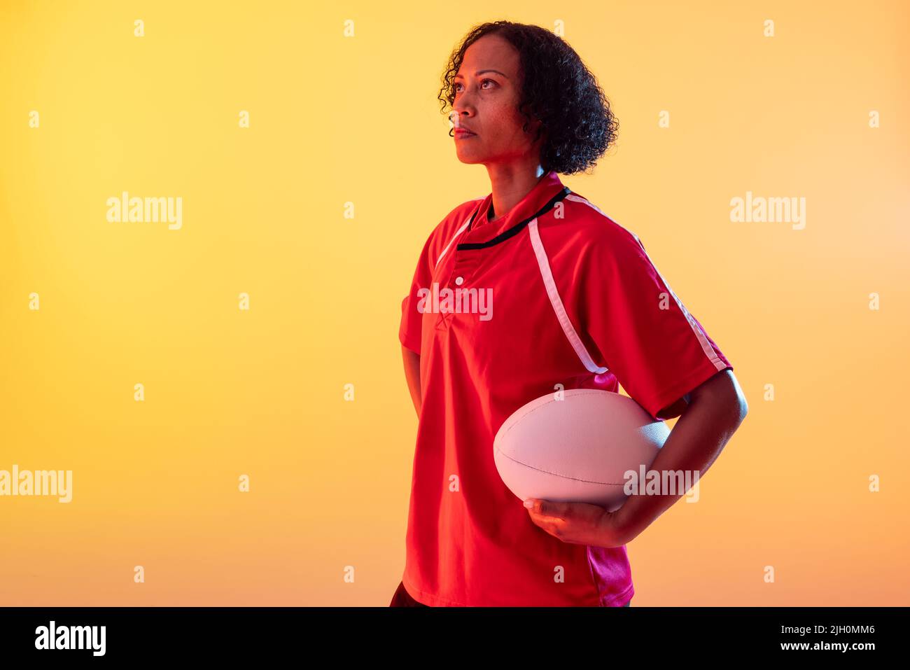 African american female rugby player with rugby ball over neon yellow ...
