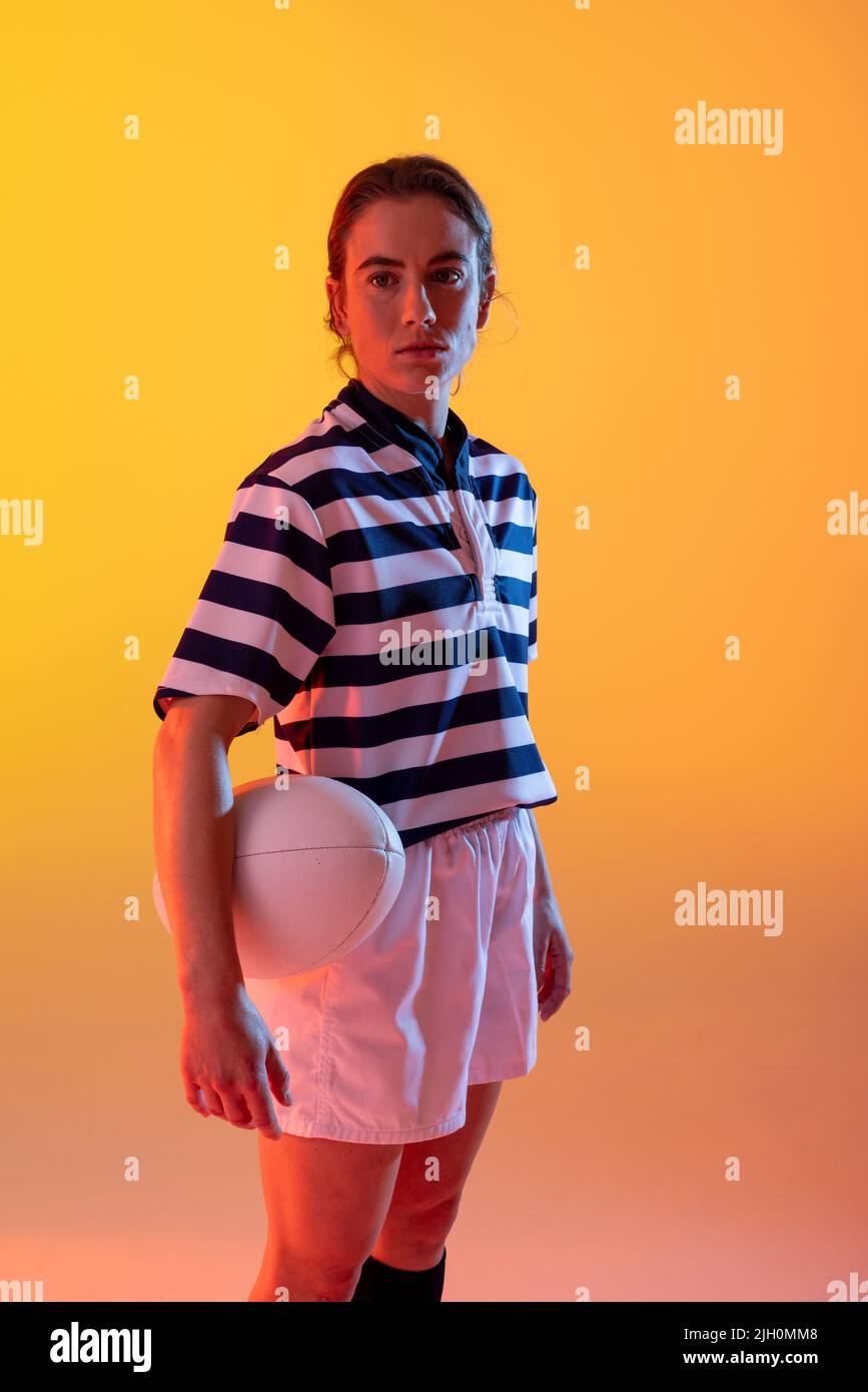 Portrait of caucasian female rugby player with rugby ball over neon ...