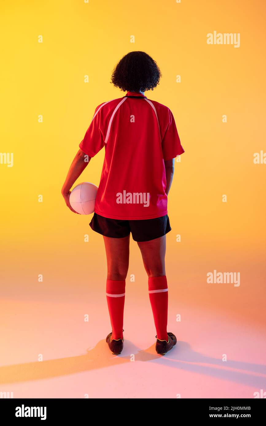 Rear view of african american female rugby player with rugby ball over ...