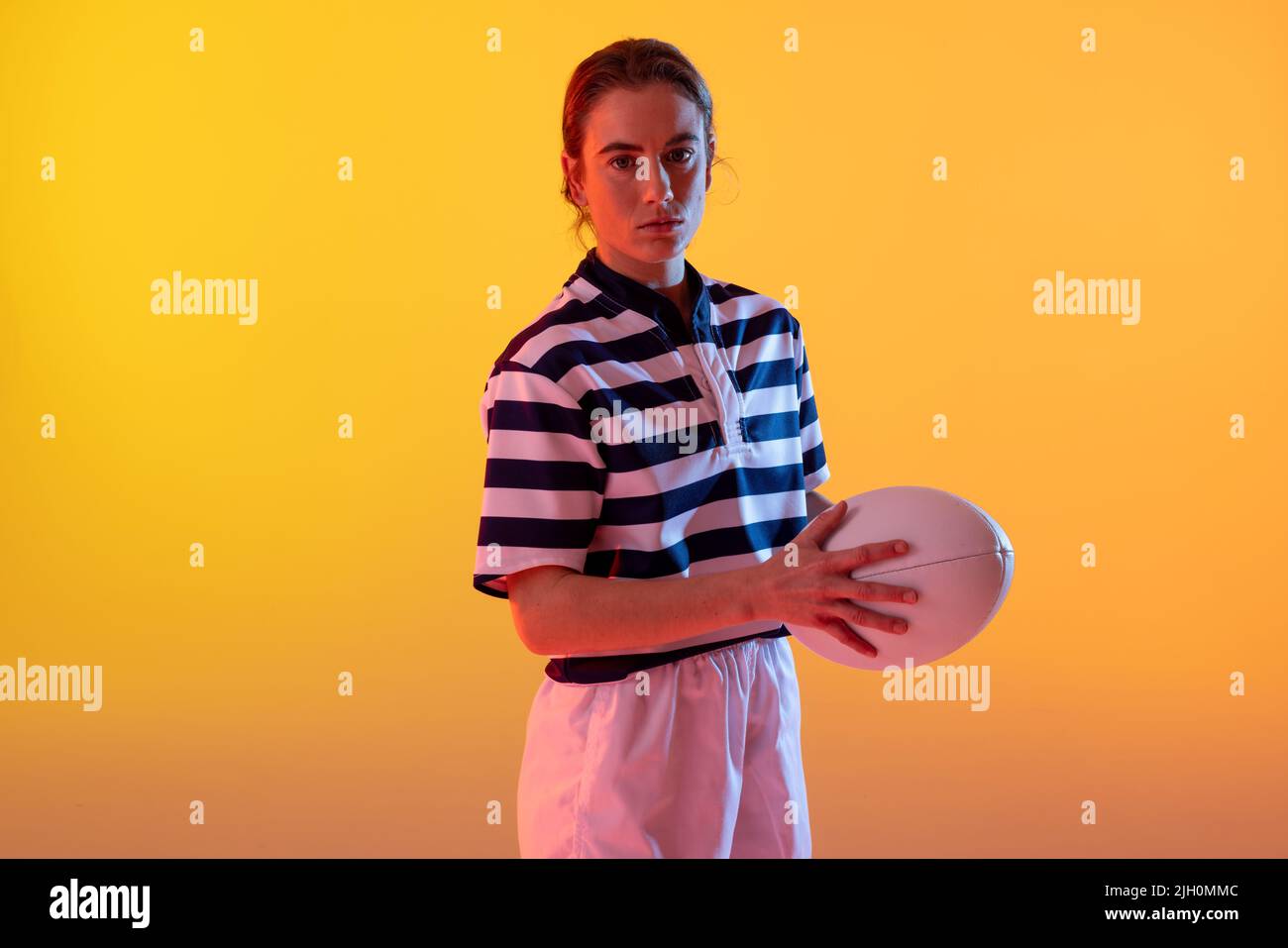 Portrait of caucasian female rugby player with rugby ball over neon ...