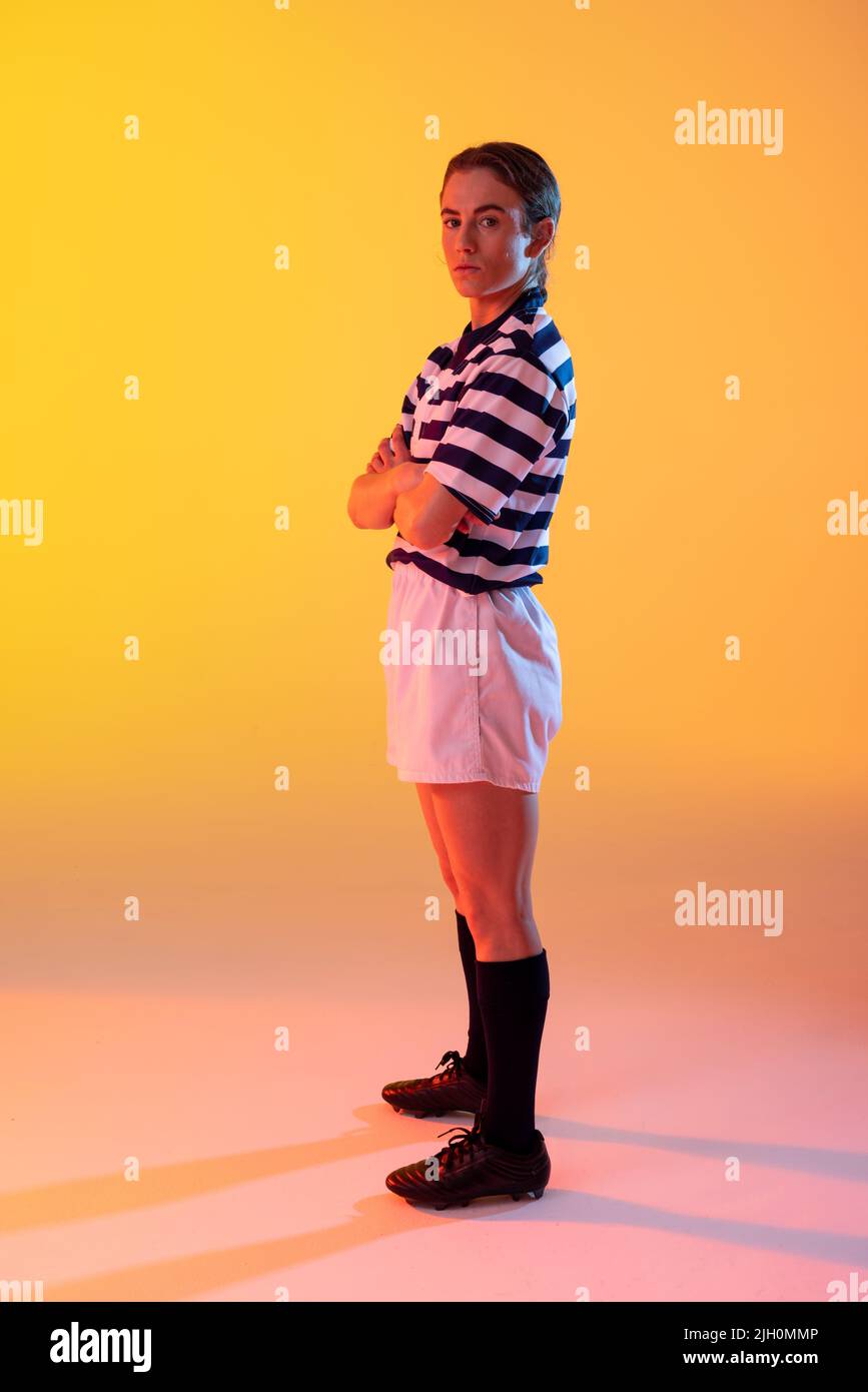 Portrait of caucasian female rugby player with arms crossed over neon ...