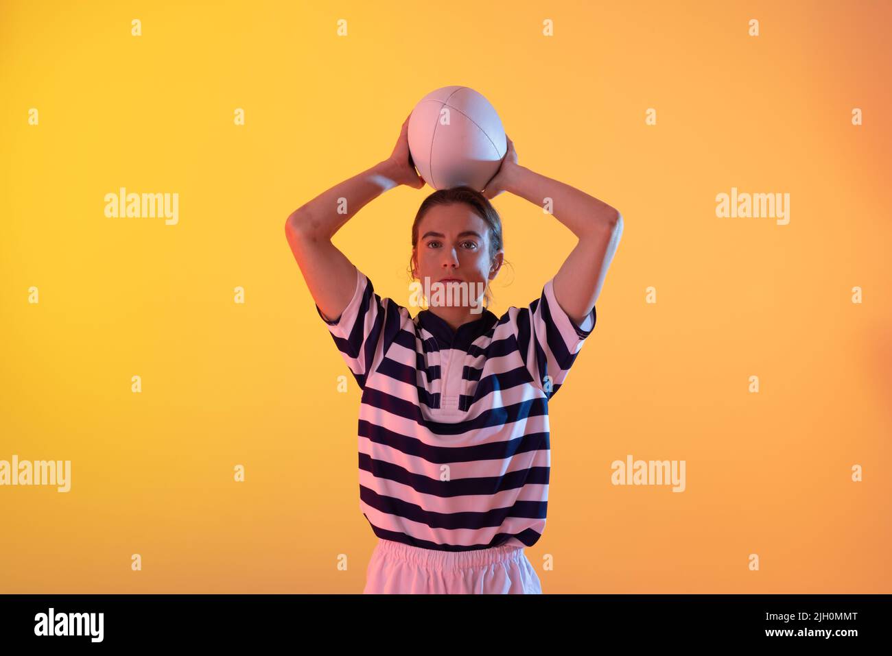 Portrait of caucasian female rugby player with rugby ball over neon ...