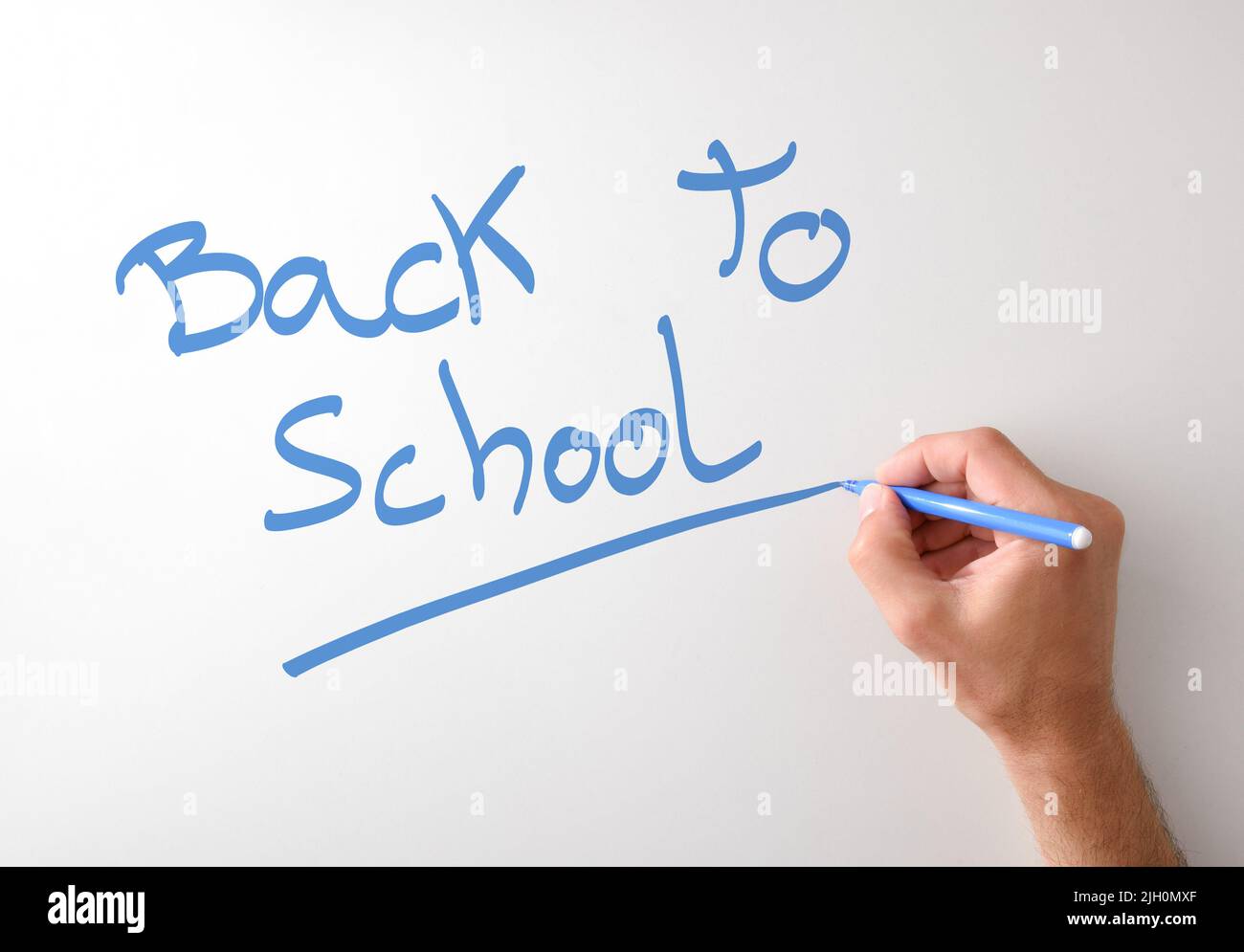 Hand writing back to school on white board with a blue marker with ...