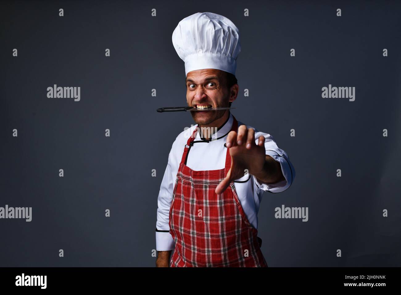 Male chef posing angry expression with knife in mouth Stock Photo - Alamy