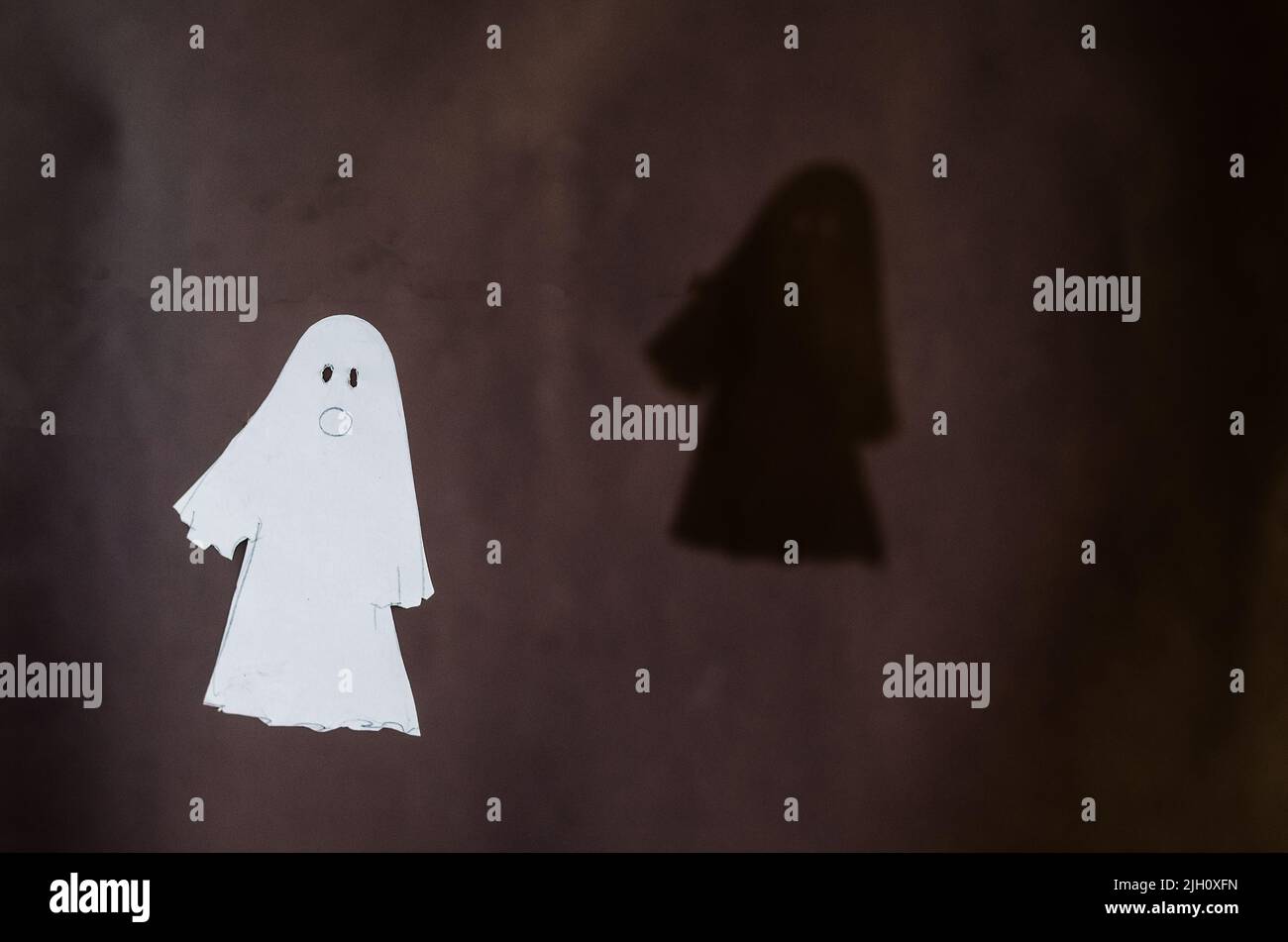A white paper ghost and his shadow on a gray wall. Halloween ...