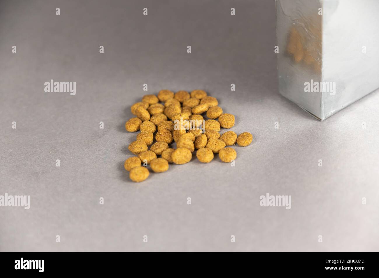 A silver rectangular box against a gray background. Pet food spilling ...