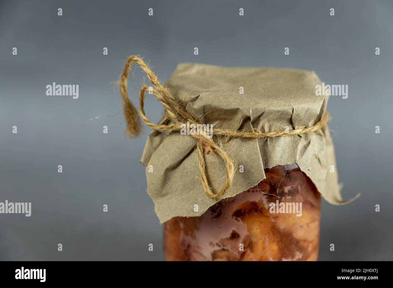 A glass jar of canned meat. Homemade stew in front of the gray ...