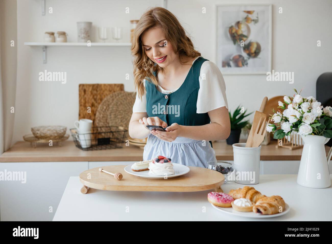 Beautiful girl confectioner takes a photo of a cake in the kitchen ...