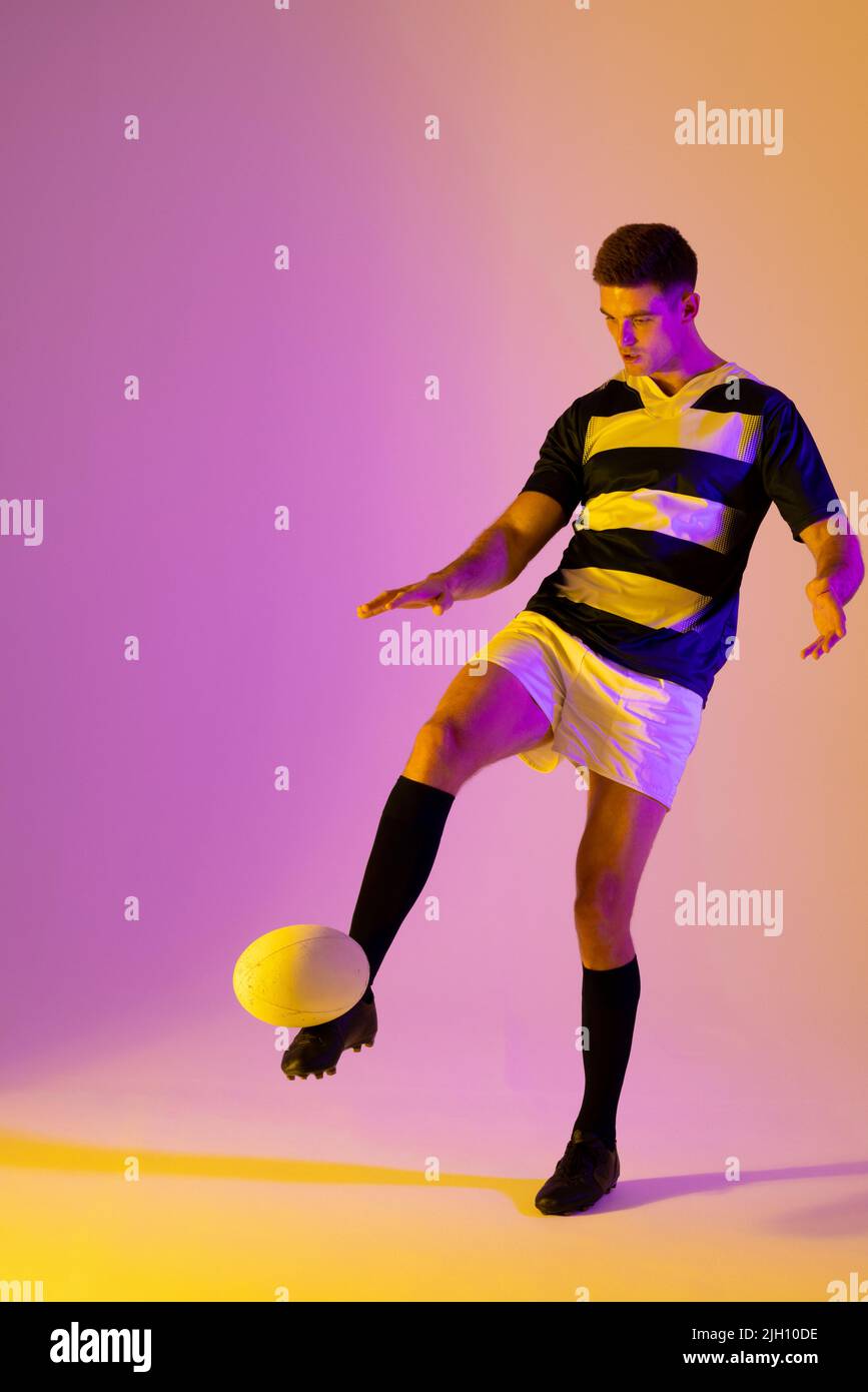 Caucasian male rugby player kicking rugby ball over pink lighting Stock ...