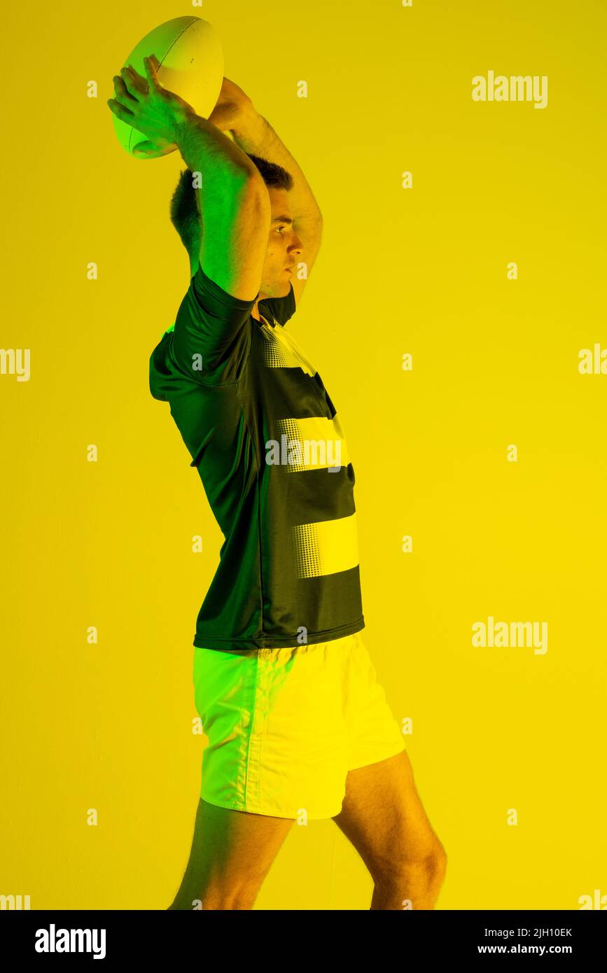 Caucasian male rugby player with rugby ball over yellow lighting Stock ...