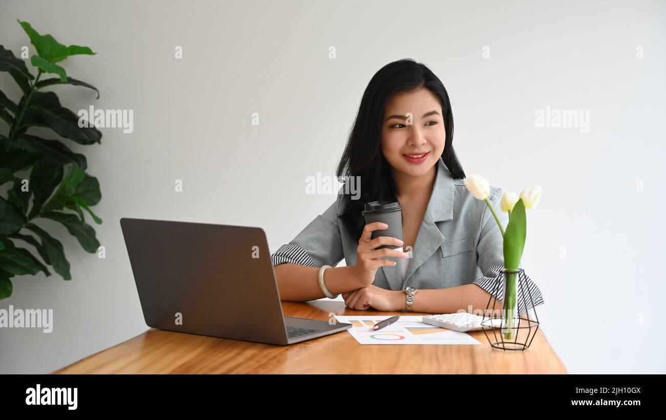 Positive asian female entrepreneur sitting front of laptop, enjoying hr ...