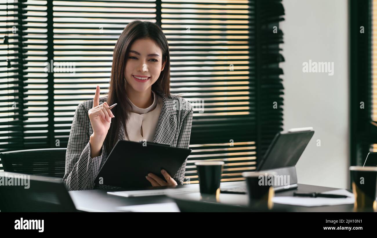 Beautiful female manager holding clipboard and communicating by video ...
