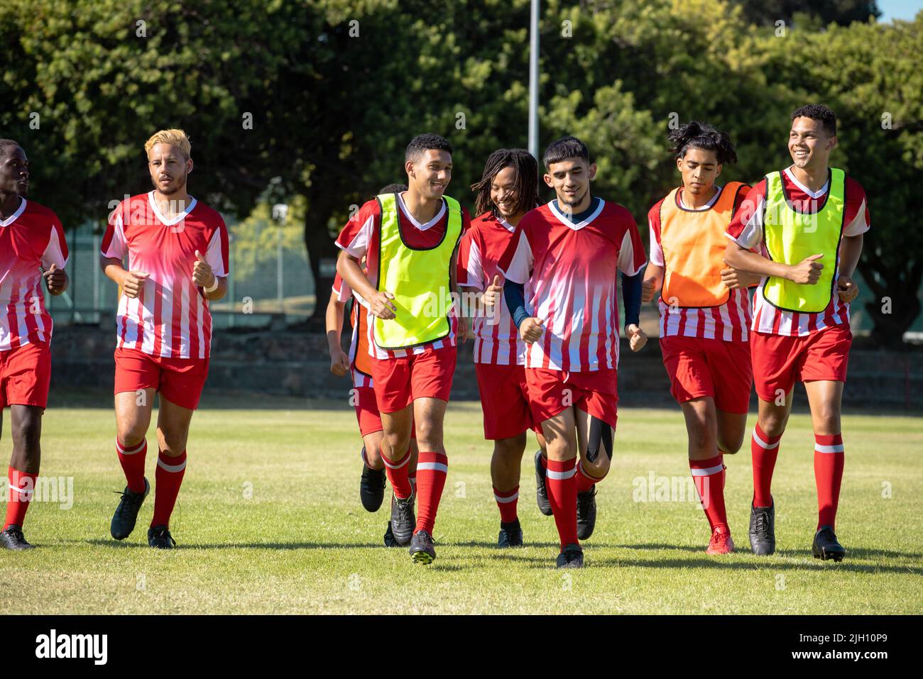 Full length of multiracial male athletes wearing red sports uniforms ...