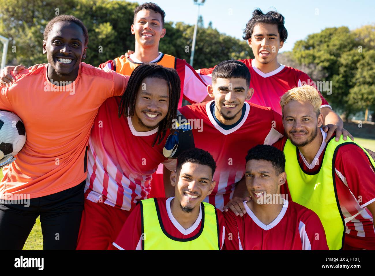 Portrait of cheerful male soccer team players wearing uniforms with ...