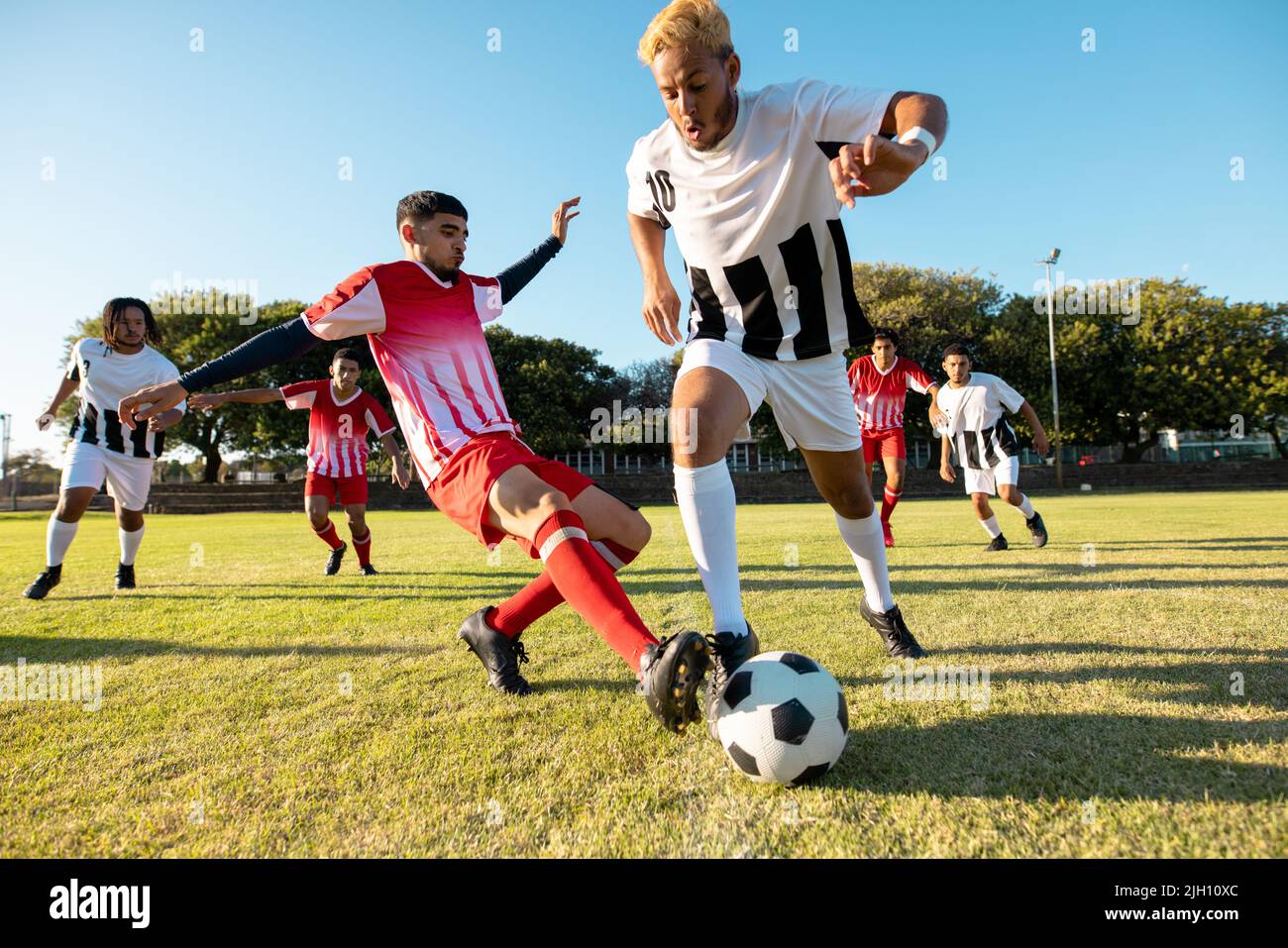 Multiracial players running and kicking the soccer ball during match in ...