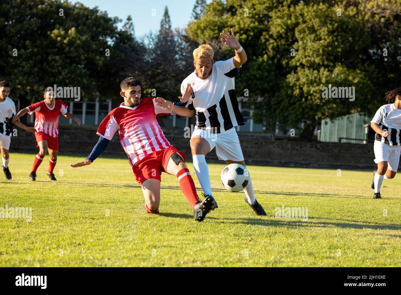 Male multiracial players running and kicking the soccer ball during ...