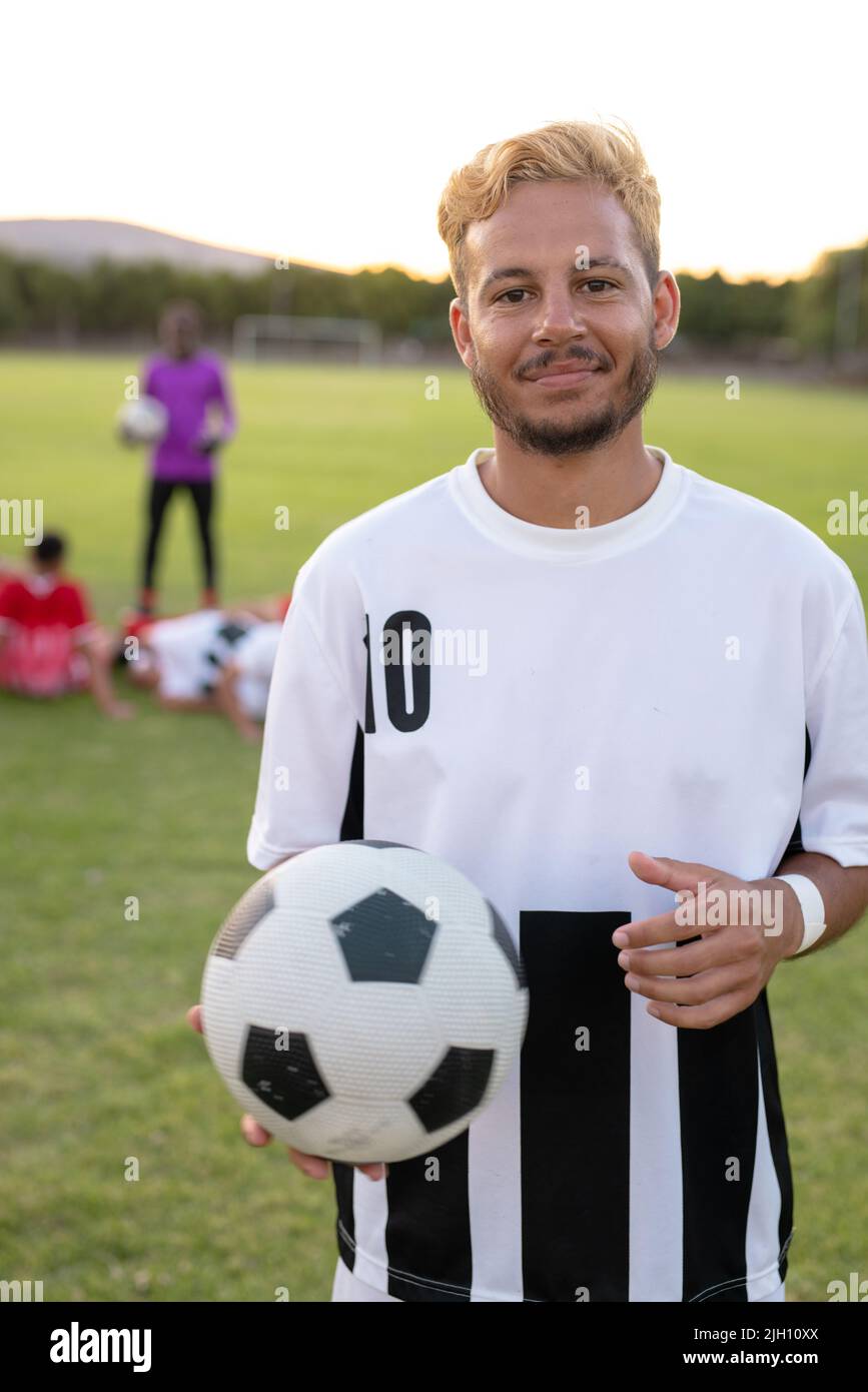 Portrait of caucasian male player in white uniform with soccer ball ...