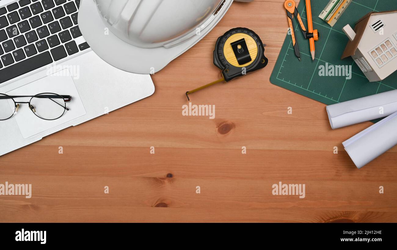 Laptop computer, glasses, protective helmet and blueprints on a wooden ...