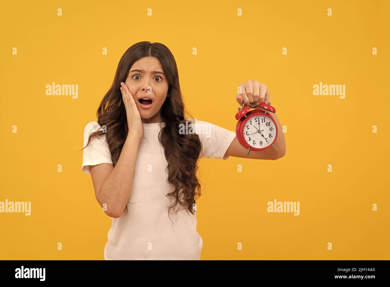 shocked kid hold retro alarm clock showing time, delay Stock Photo - Alamy
