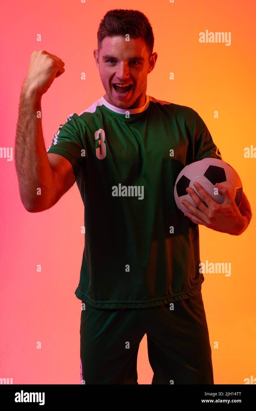 Portrait of happy caucasian male soccer player raising hand with ...