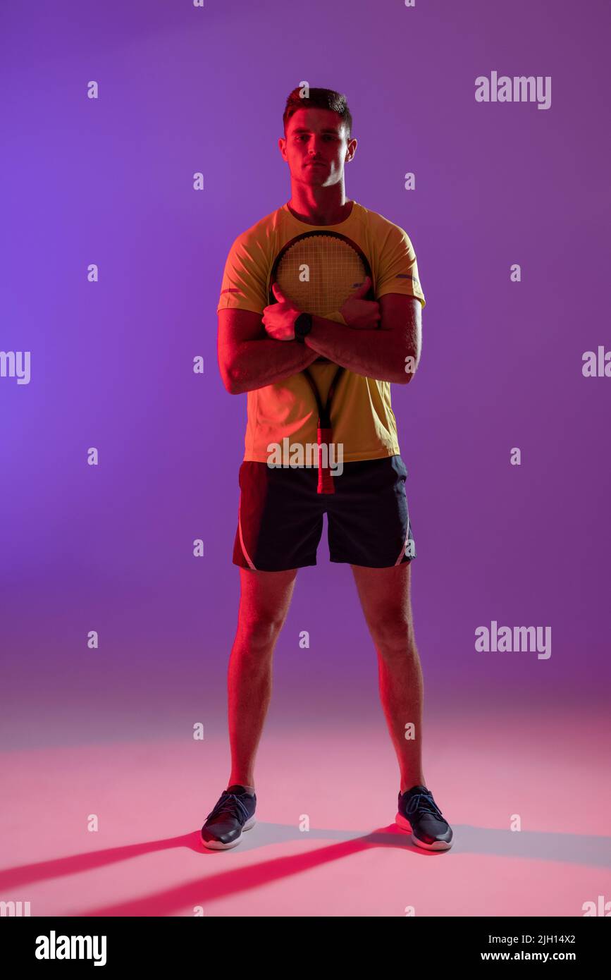 Portrait of caucasian male tennis player with tennis racket over neon ...