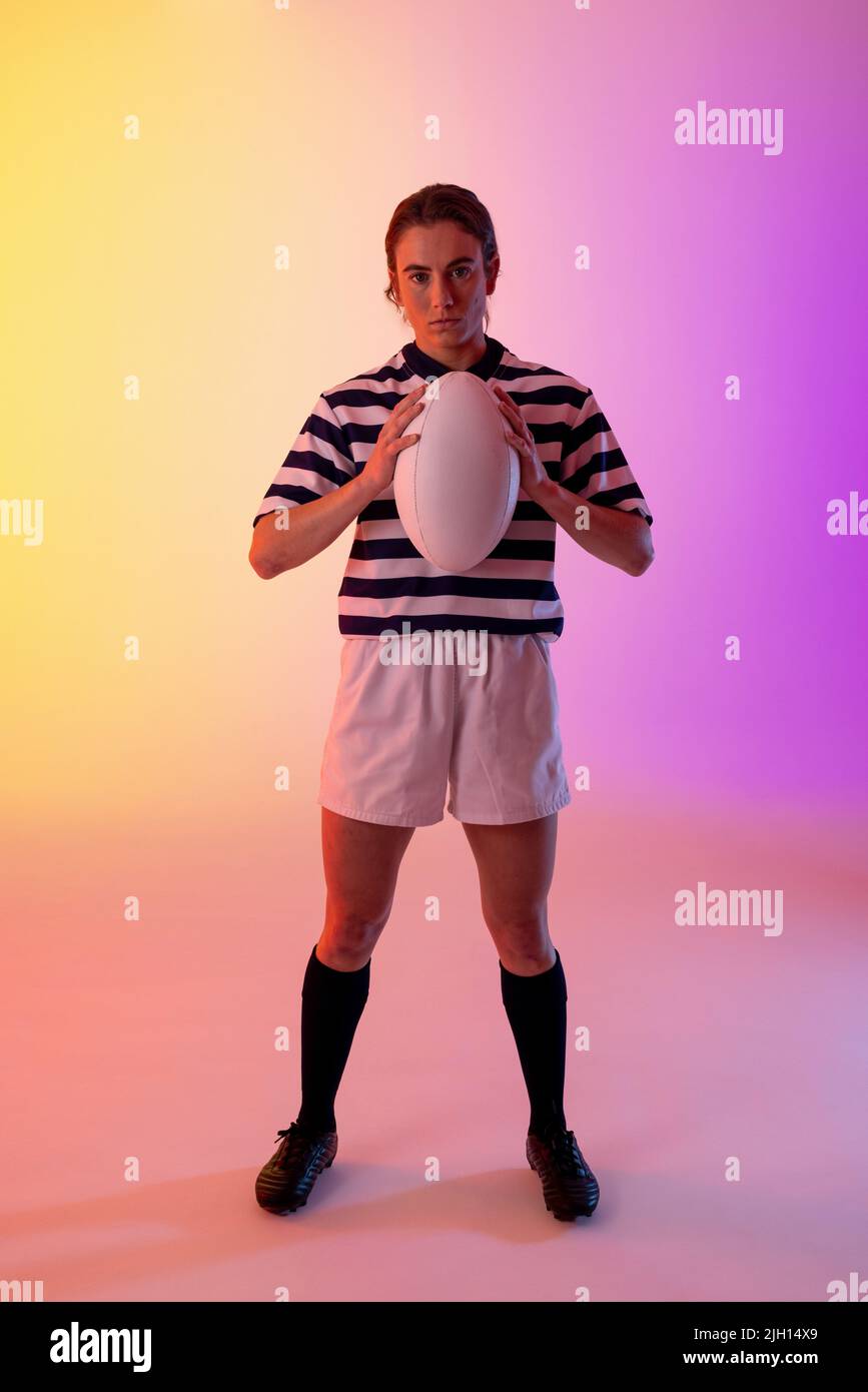 Portrait of caucasian female rugby player with rugby ball over neon ...
