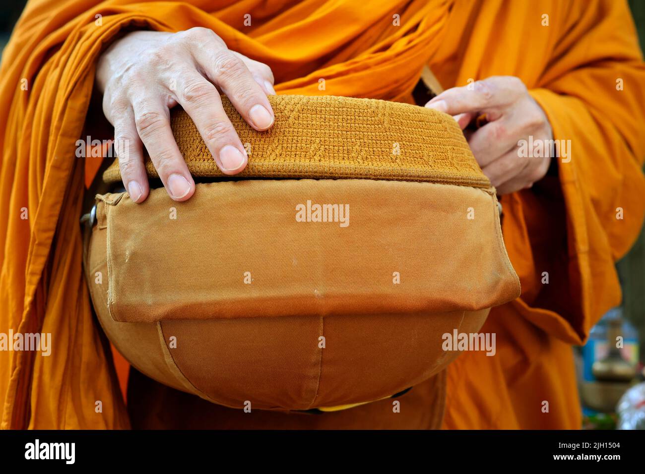 hand of monk dressing orange robe, holding bowl during reception of ...
