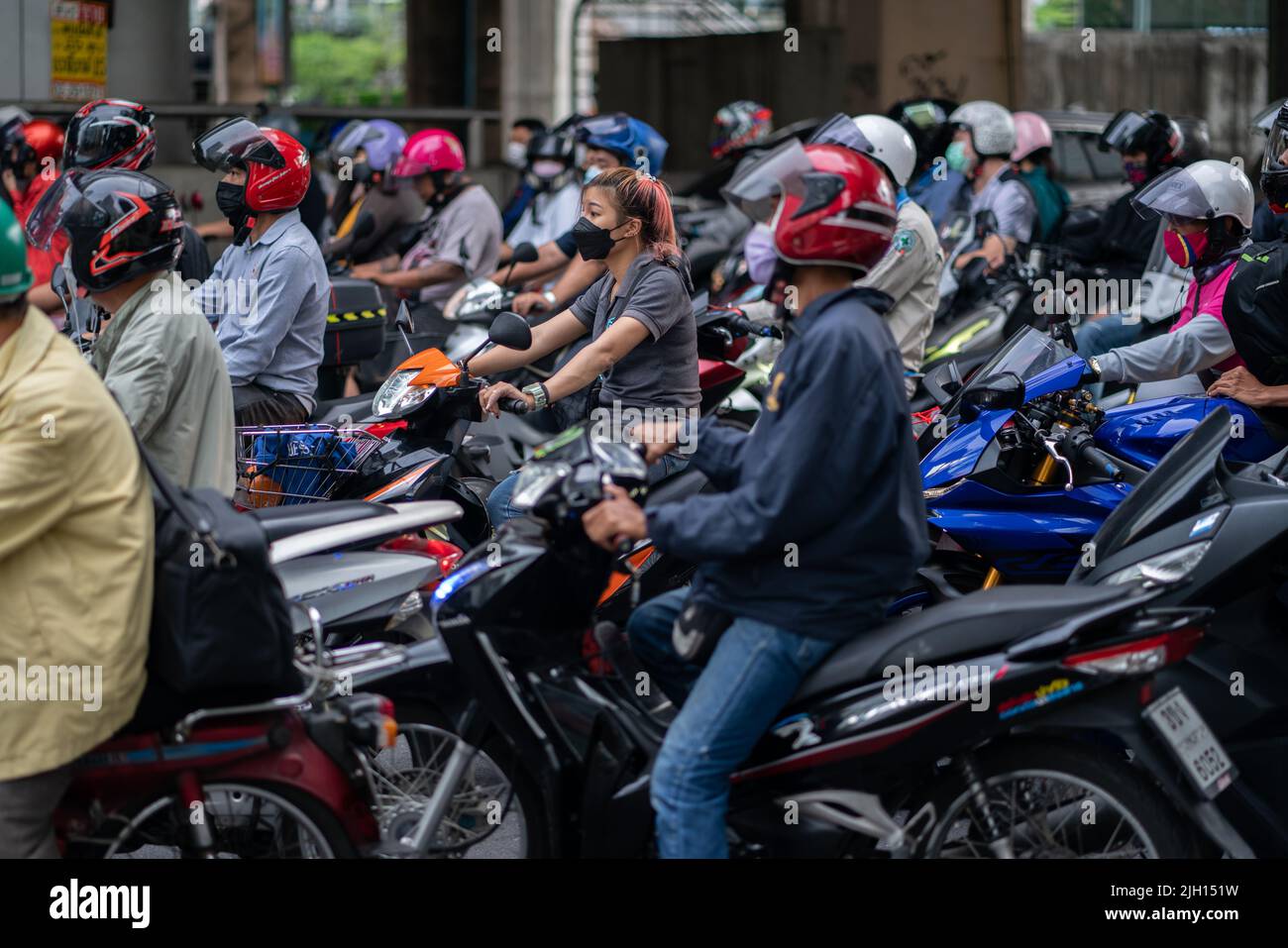 A Women on motrokbike not wearing an helmet, riders waiting at traffic ...
