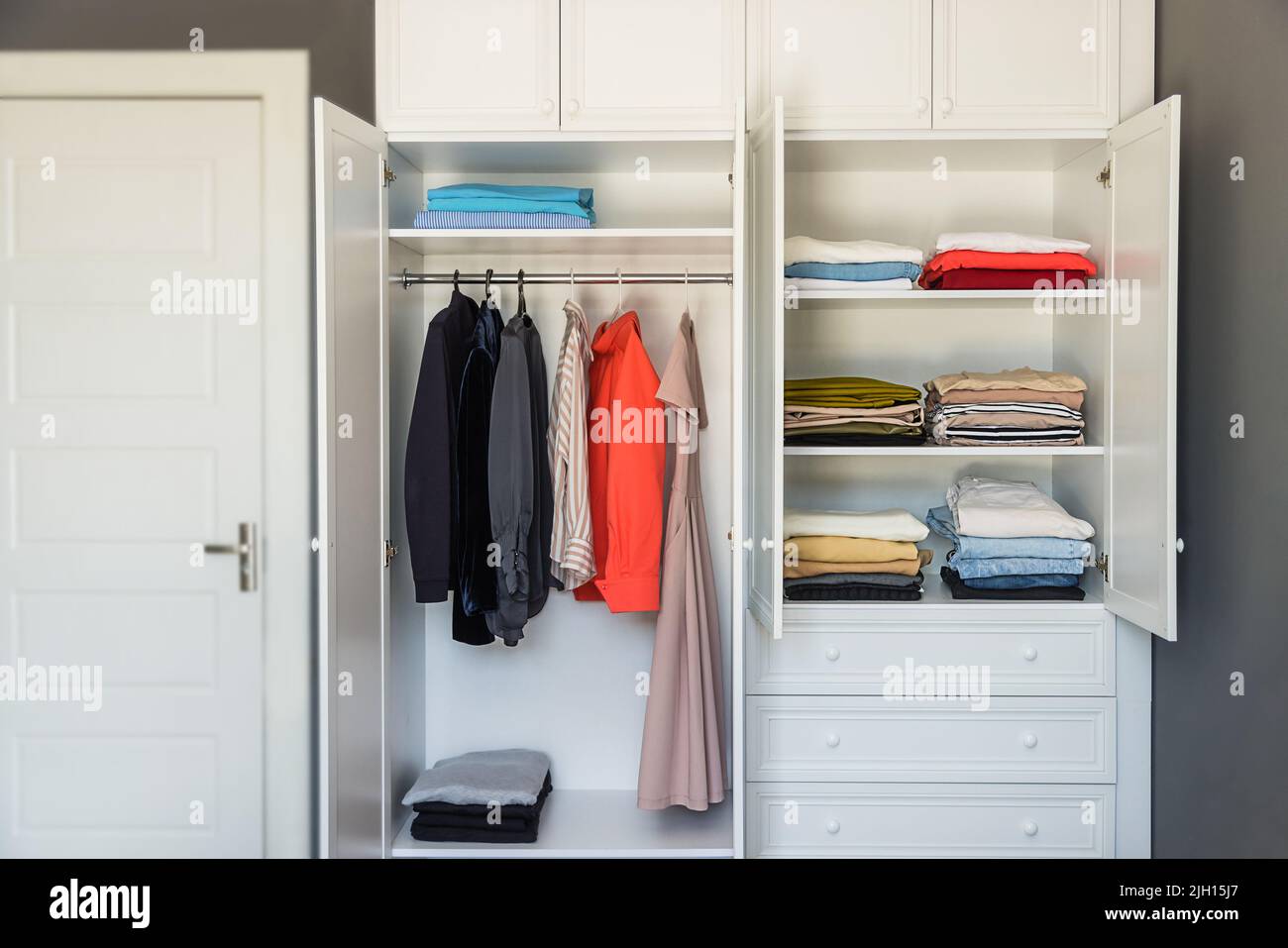 Modern dressing room, neatly hung clothes on hangers and shelves in the ...
