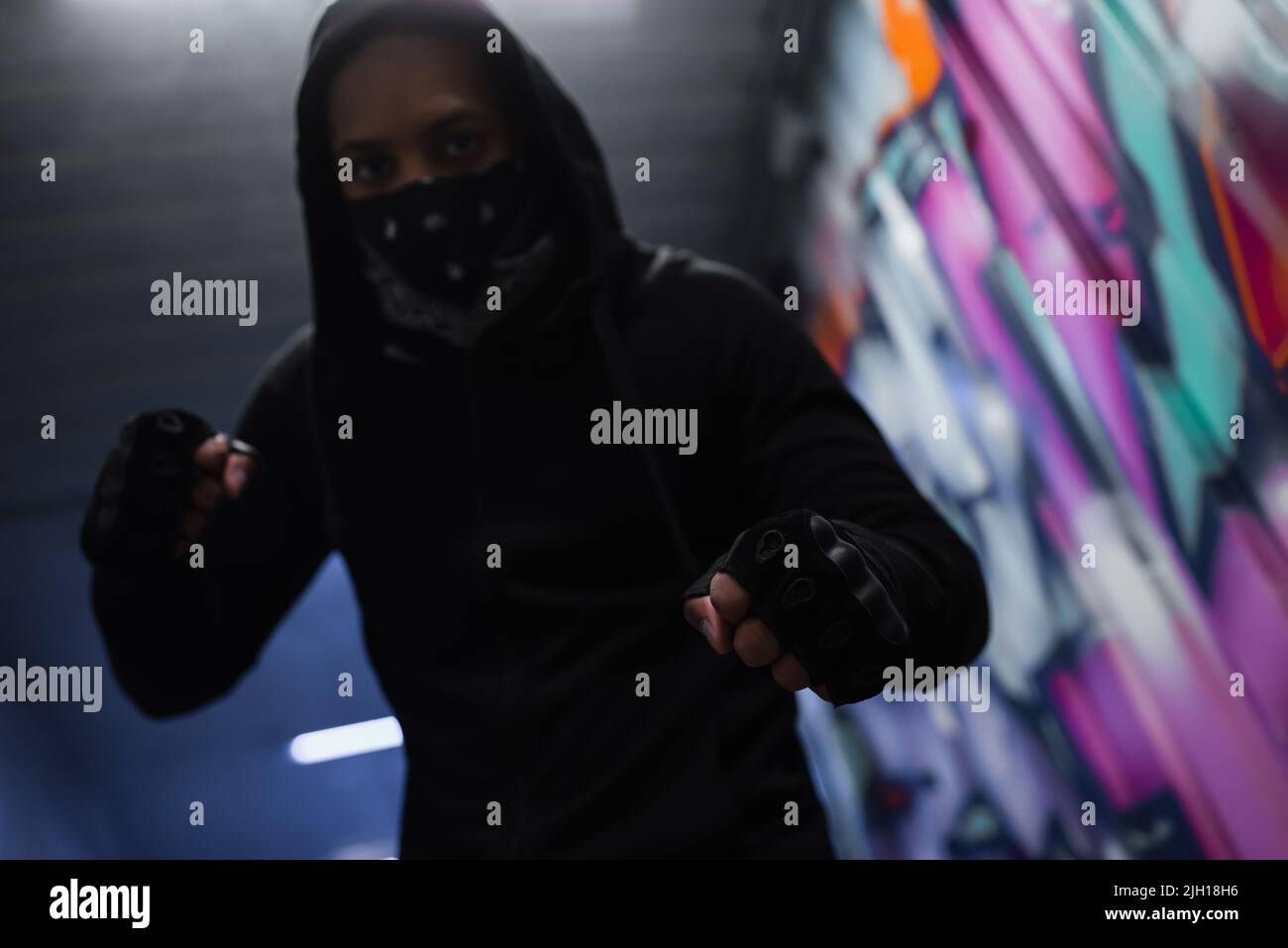 Low angle view of blurred african american hooligan in gloves and mask ...