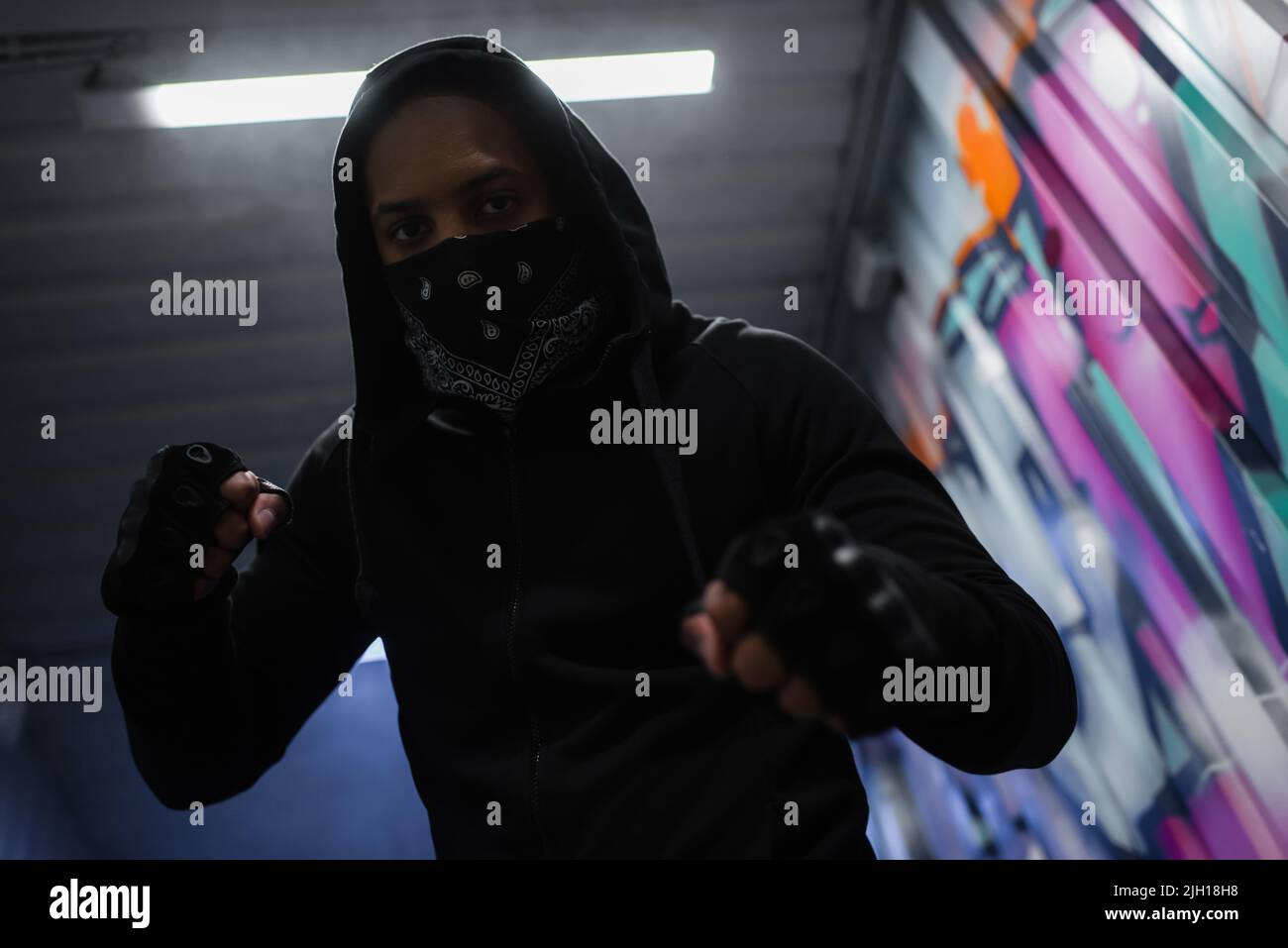 Low angle view of african american bandit in mask standing in fighting ...