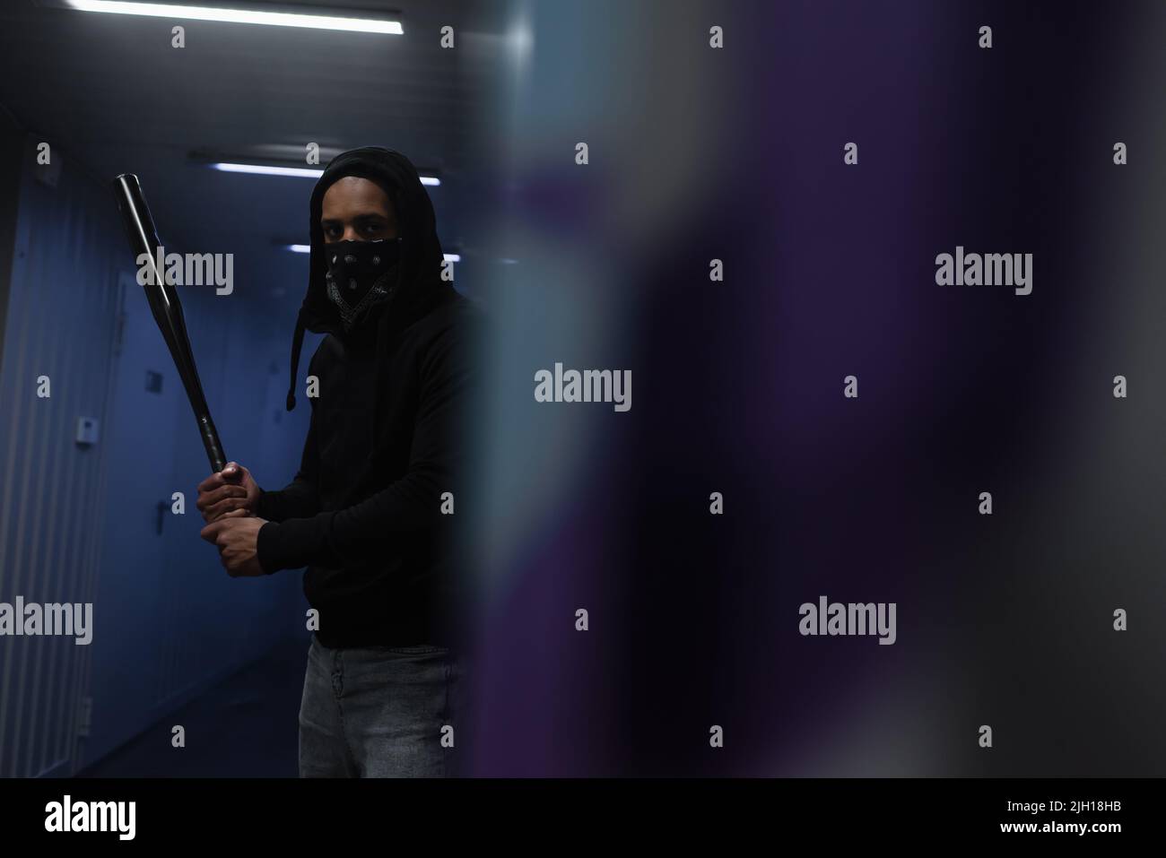 African american hooligan with mask on face holding baseball bat near ...