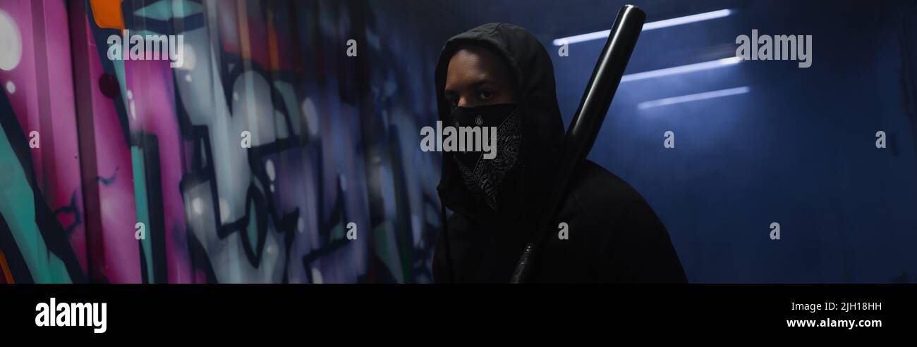 African american bandit with mask on face holding baseball bat near ...